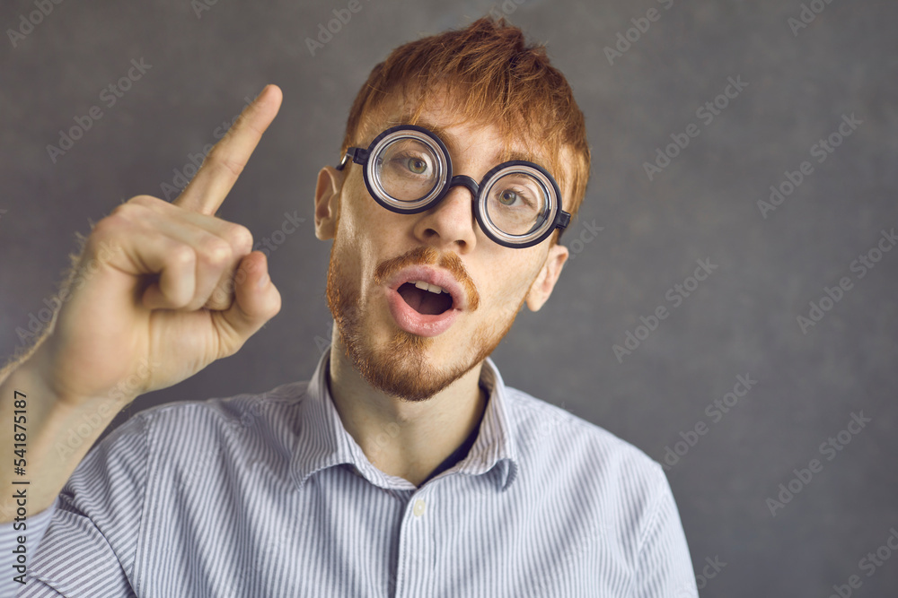 Studio portrait shot of red-headed young funny freak man wearing thick ...