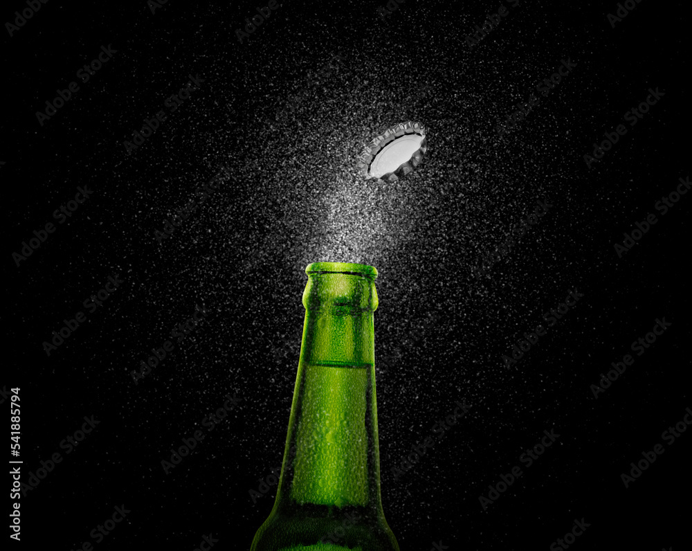 Closeup photo of an green beer bottle splashing beer drops on a black ...