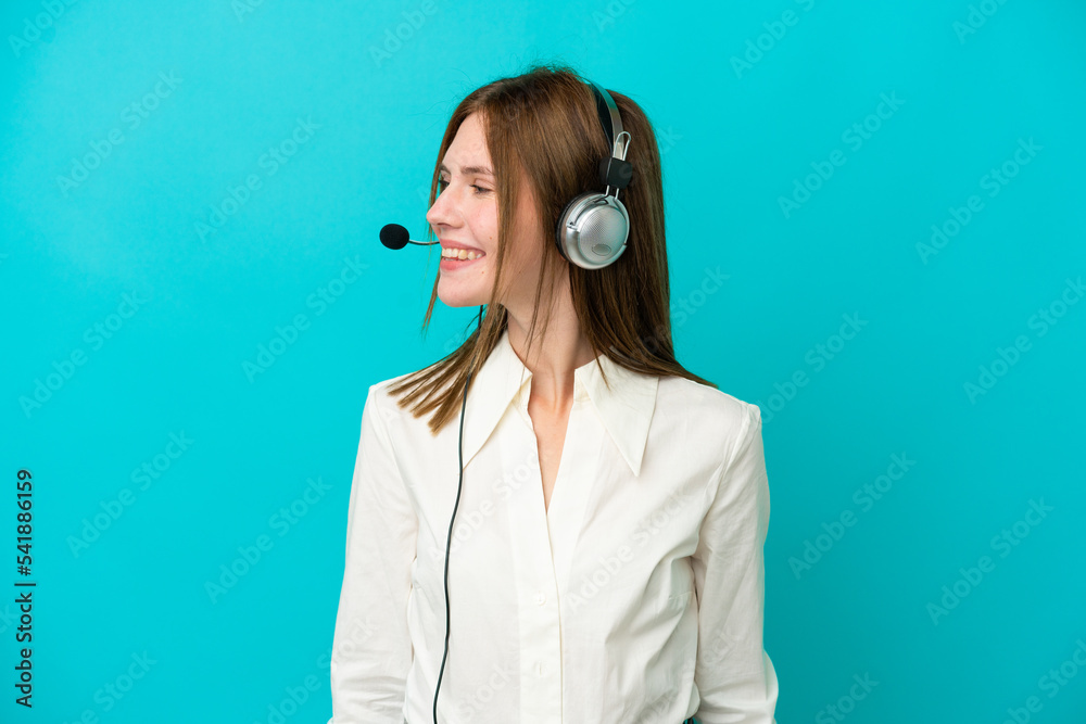 Telemarketer English woman working with a headset isolated on blue ...