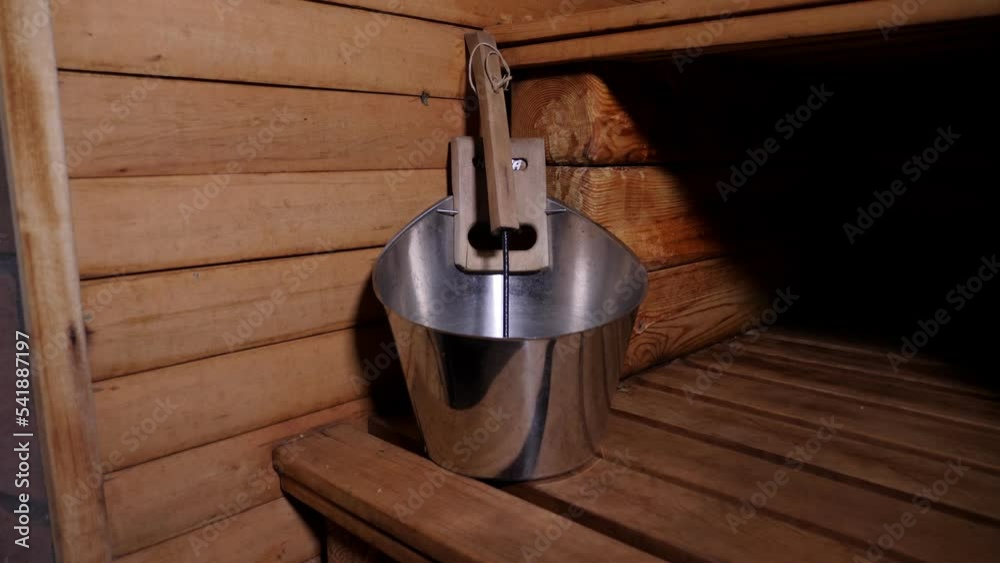 Metal bucket with wooden handle and ladle on a wooden shelf in a ...