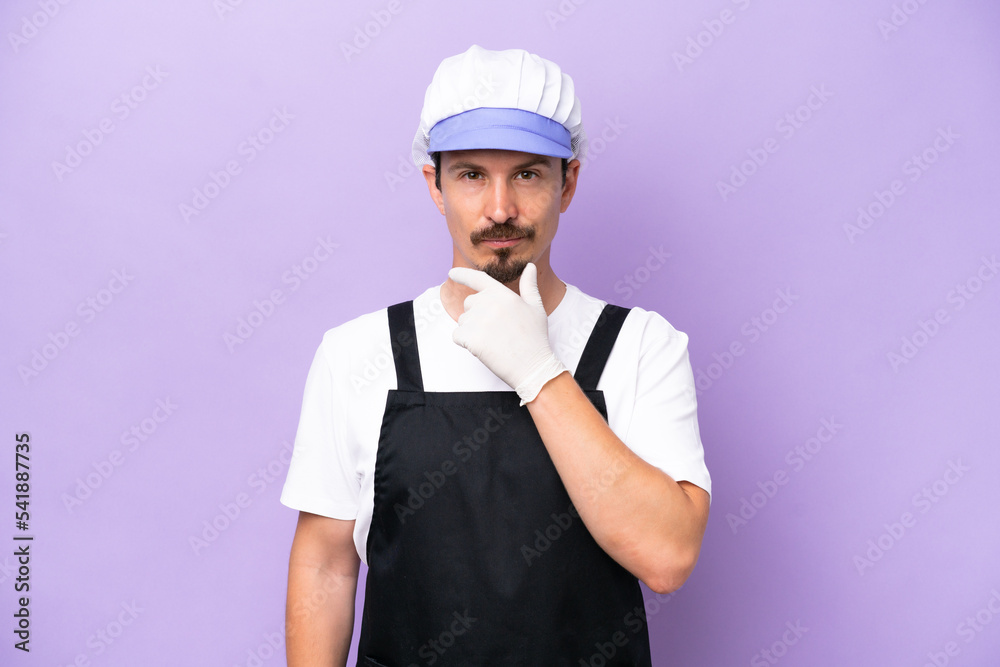 Fishmonger man wearing an apron isolated on purple background thinking ...