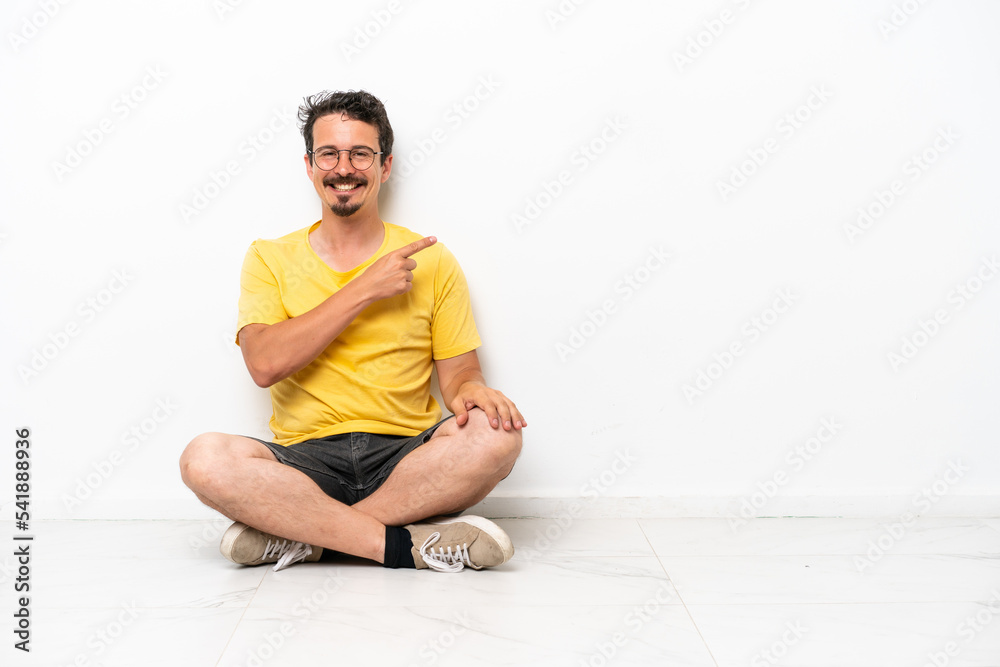 Young caucasian man sitting on the floor isolated on white background ...