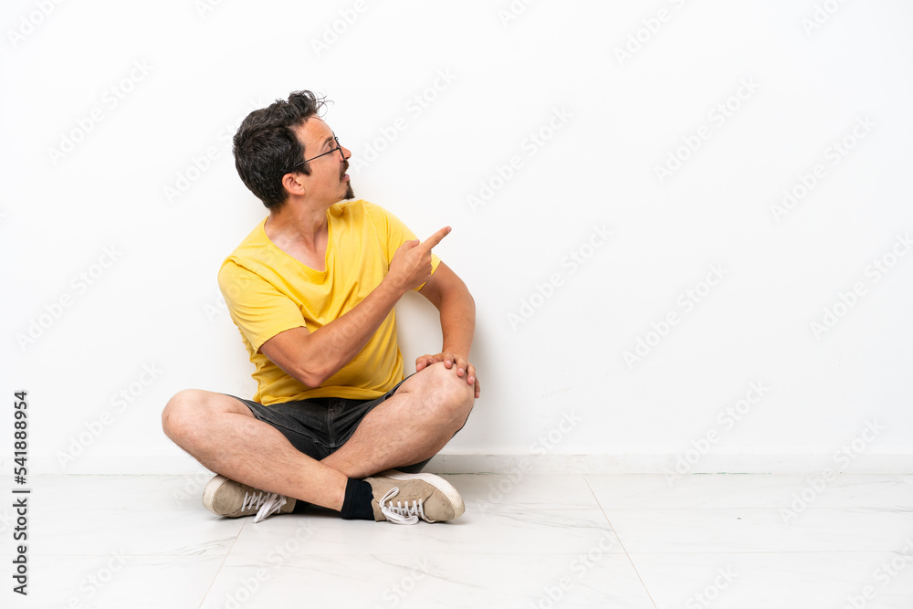 Young caucasian man sitting on the floor isolated on white background ...