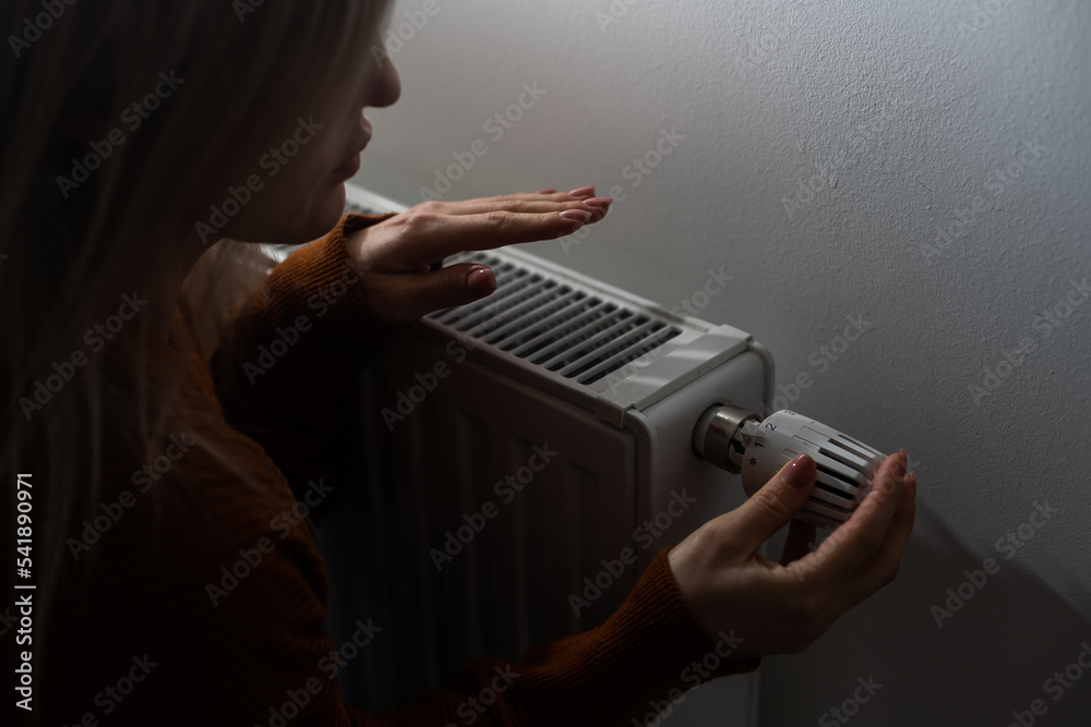 Woman warming her hands on the heater, close-up. Hands and heater ...