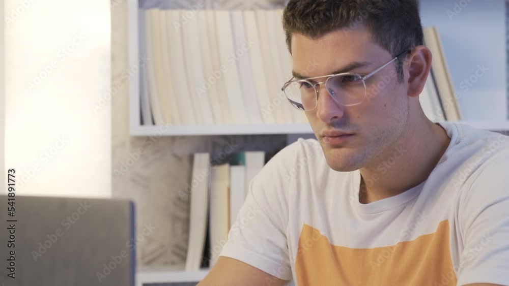 Student doing research on his computer at home. University student ...