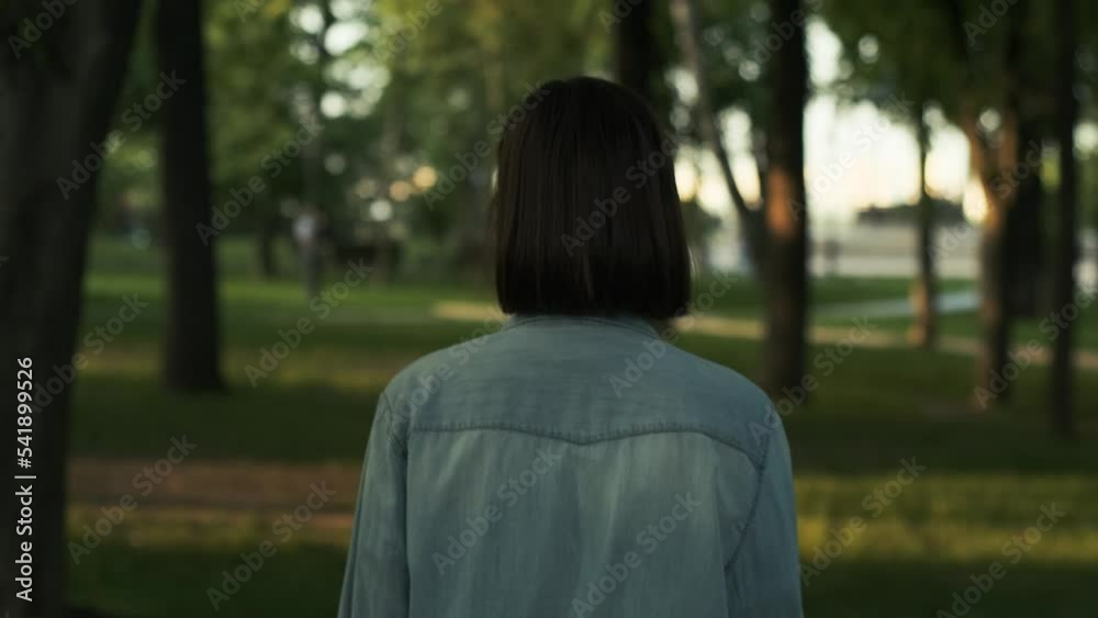 Young woman walking and thinking in the park. Following carefree ...