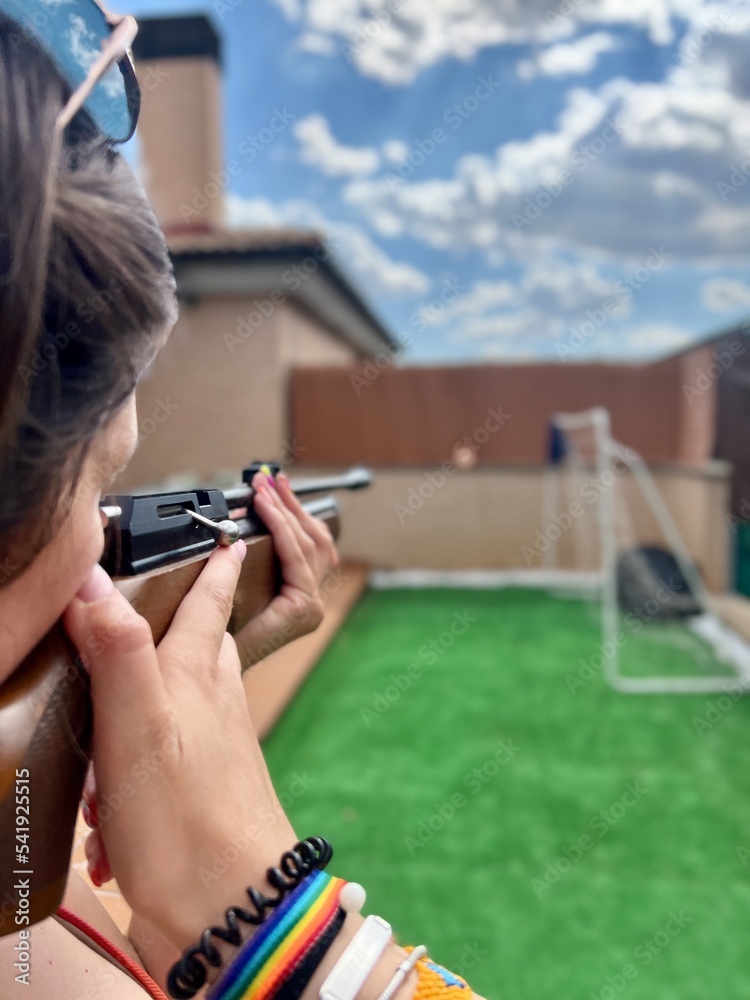 Foto de Rear view of a woman using a rifle aiming. Close up of a woman ...