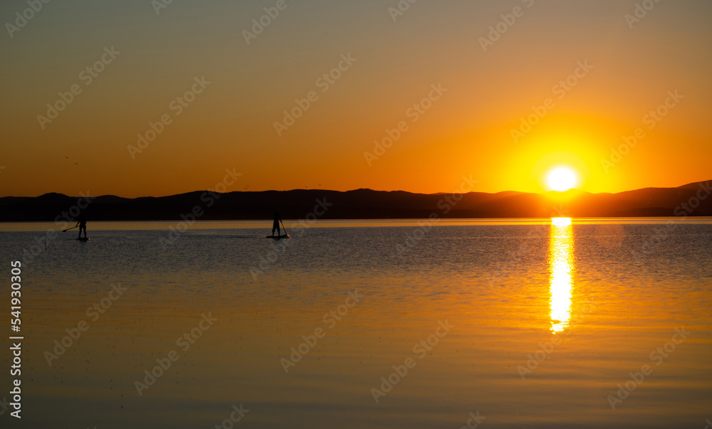 A man and a woman are sailing on a sapa along a mountain lake against ...