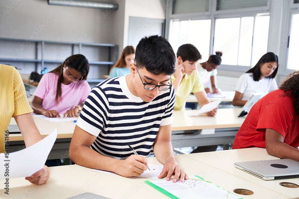 Student taking notes while studying in high school. Satisfied young man ...