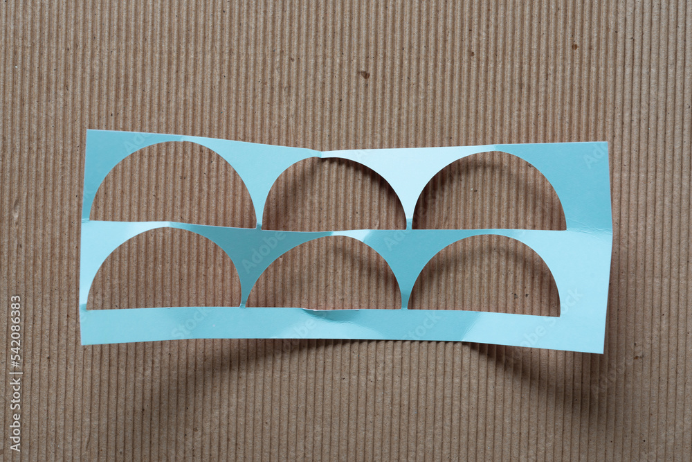 partly crumpled paper stencil with half-circle cutouts on corrugated ...