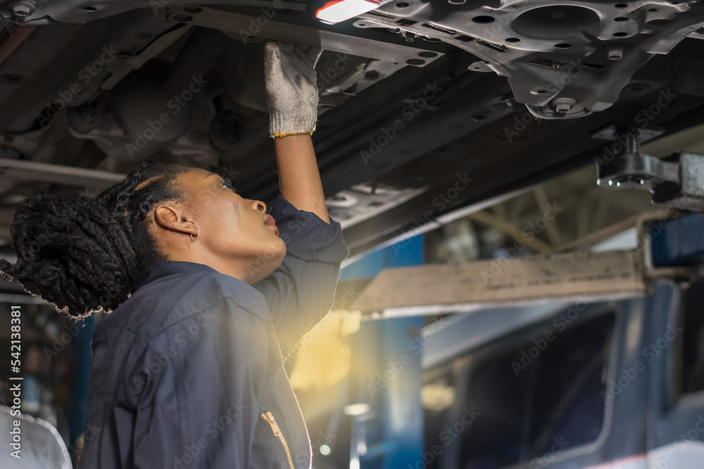 African black mechanic woman working underneath car in auto garage ...