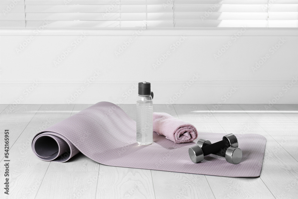 Foto de Exercise mat, dumbbells, towel and bottle of water on light ...