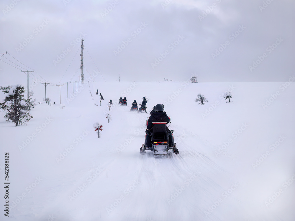 A group of tourists riding Snowmobiles on Glacier through the snowy ...