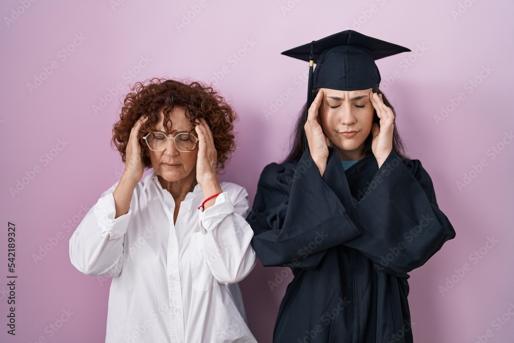 Hispanic mother and daughter wearing graduation cap and ceremony robe ...