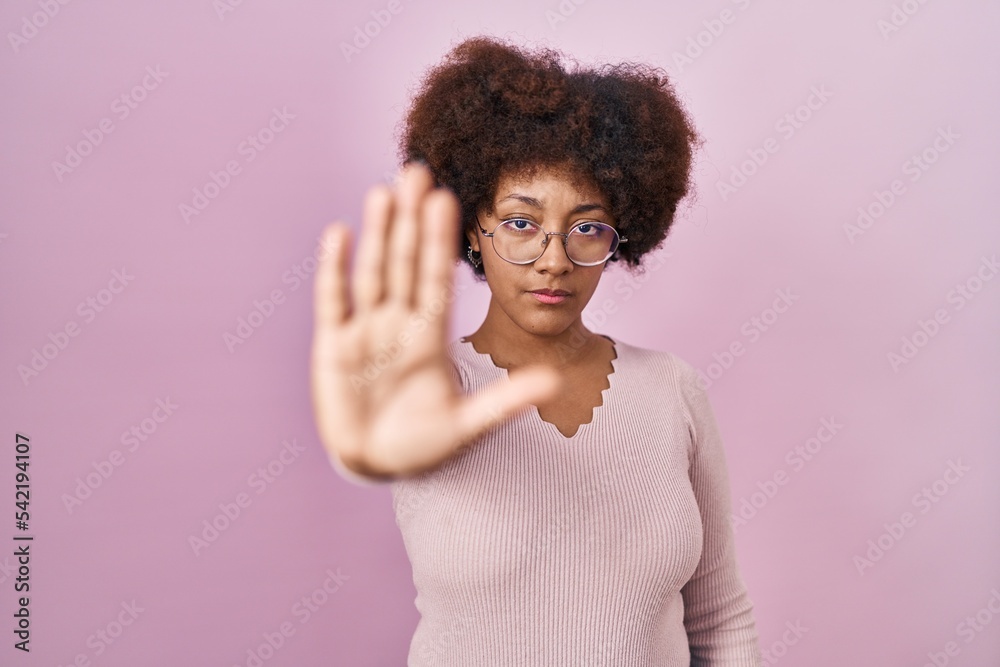 Young african american woman standing over pink background doing stop ...
