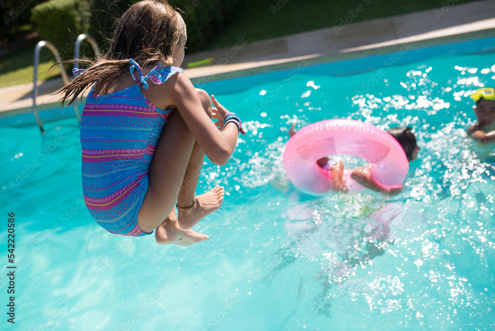Back view of girl in swimsuit jumping into swimming pool. Little girl ...