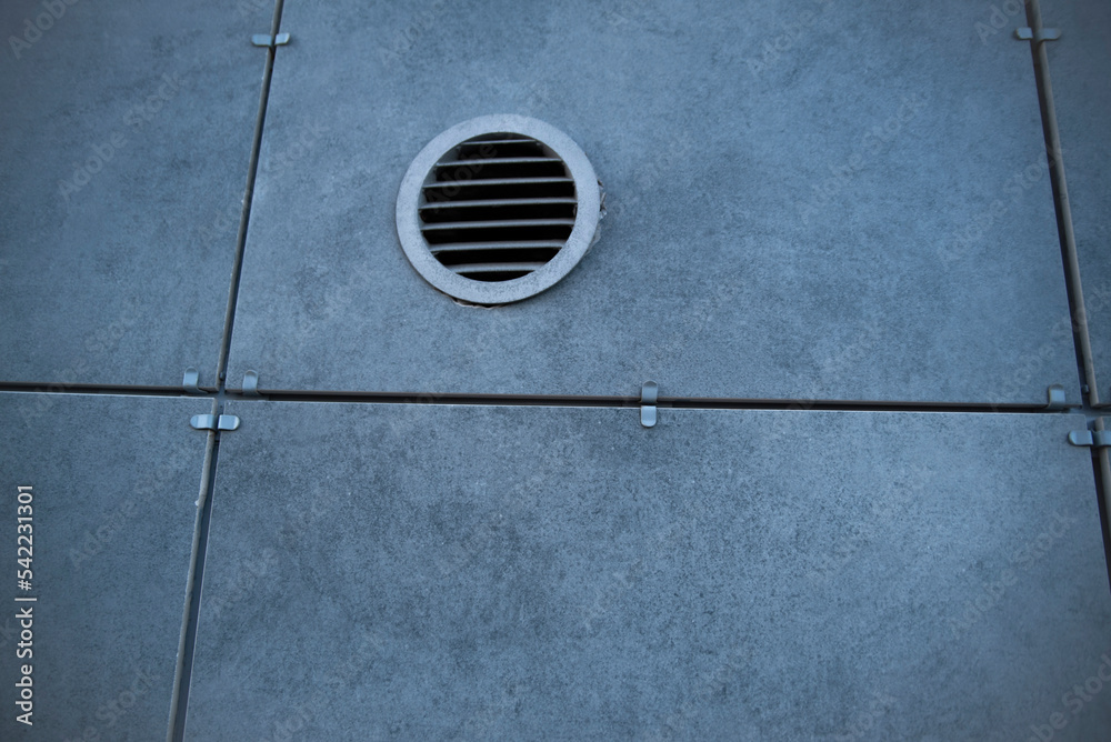 Ventilation hole in the gray panel wall of an industrial building ...
