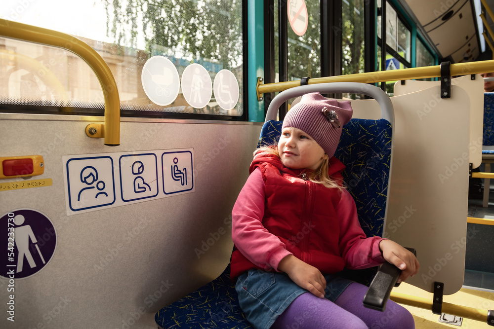 Adorable child rides bus of public modern transport looks out window ...