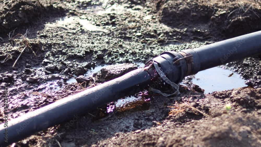 Water dripping from a leaky pipe in farm land. flows from a rusty water ...