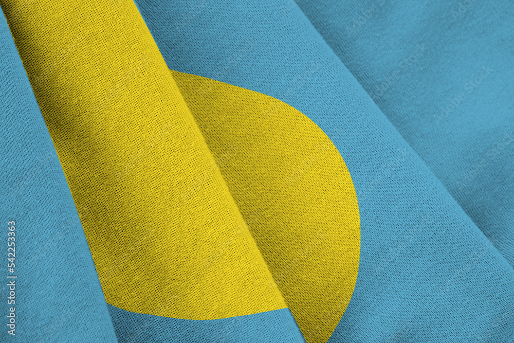 Palau flag with big folds waving close up under the studio light ...