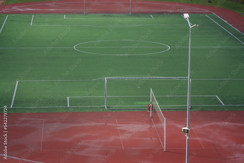 Empty school stadium with synthetic green field and red treadmills in ...