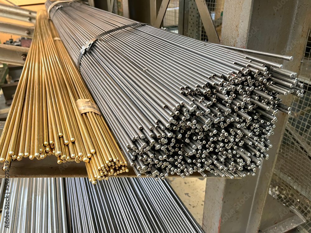 rack full of steel and brass elongated bars, raw material for shafts ...