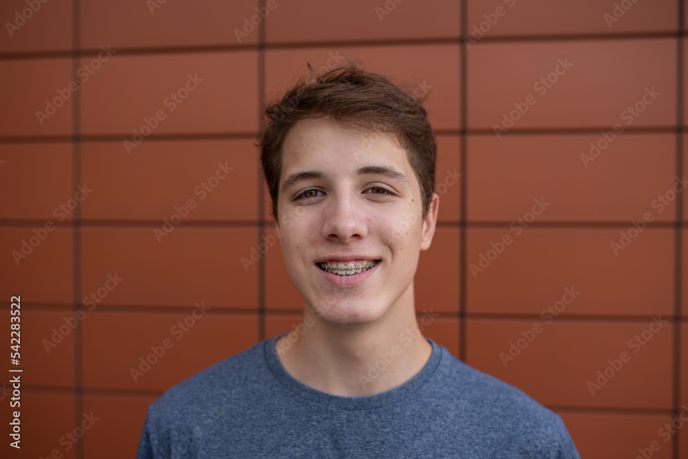 Smiling young guy wearing teeth braces and having mild acne on his face ...