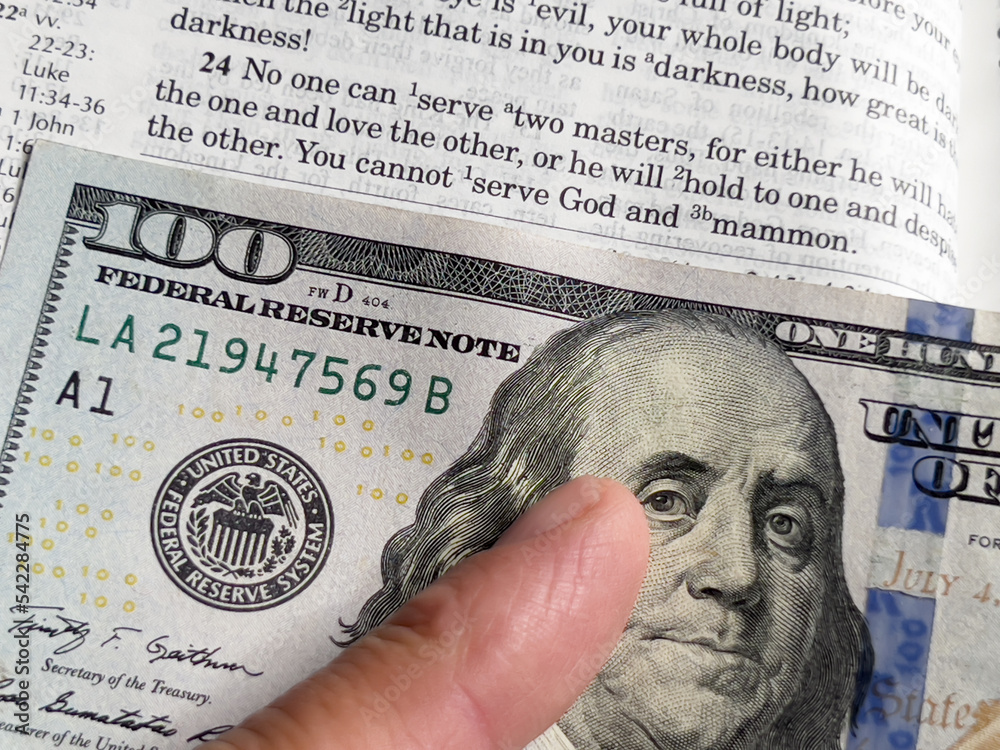 The Holy Bible in English with a tab from the $ 100 banknote showing a ...