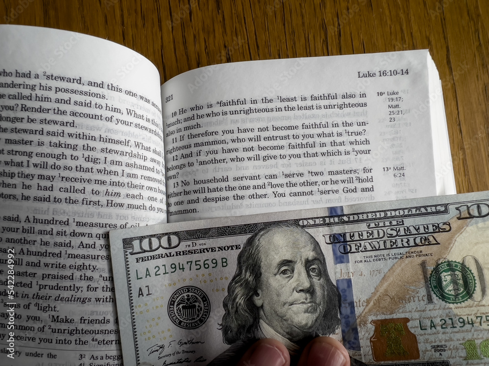The Holy Bible in English with a tab from the US $ 100 banknote showing ...
