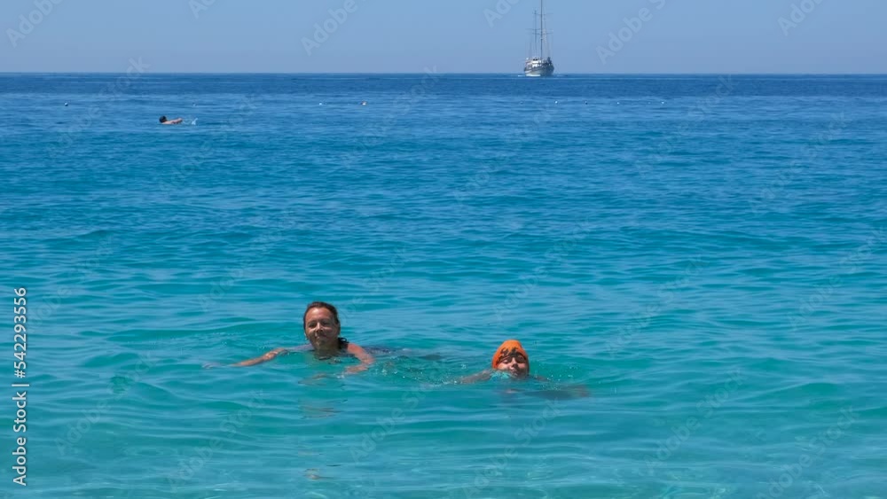 Mum and child swimming in blue sea. A view of mother with her little ...