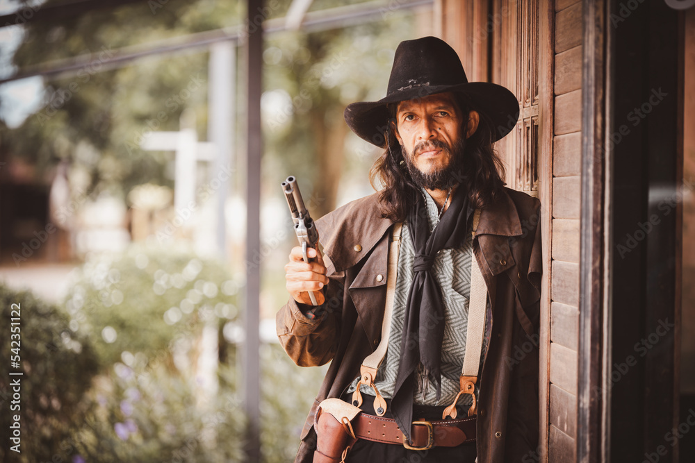 Portrait cowboy wearing in western style suite with hat posing show gun ...