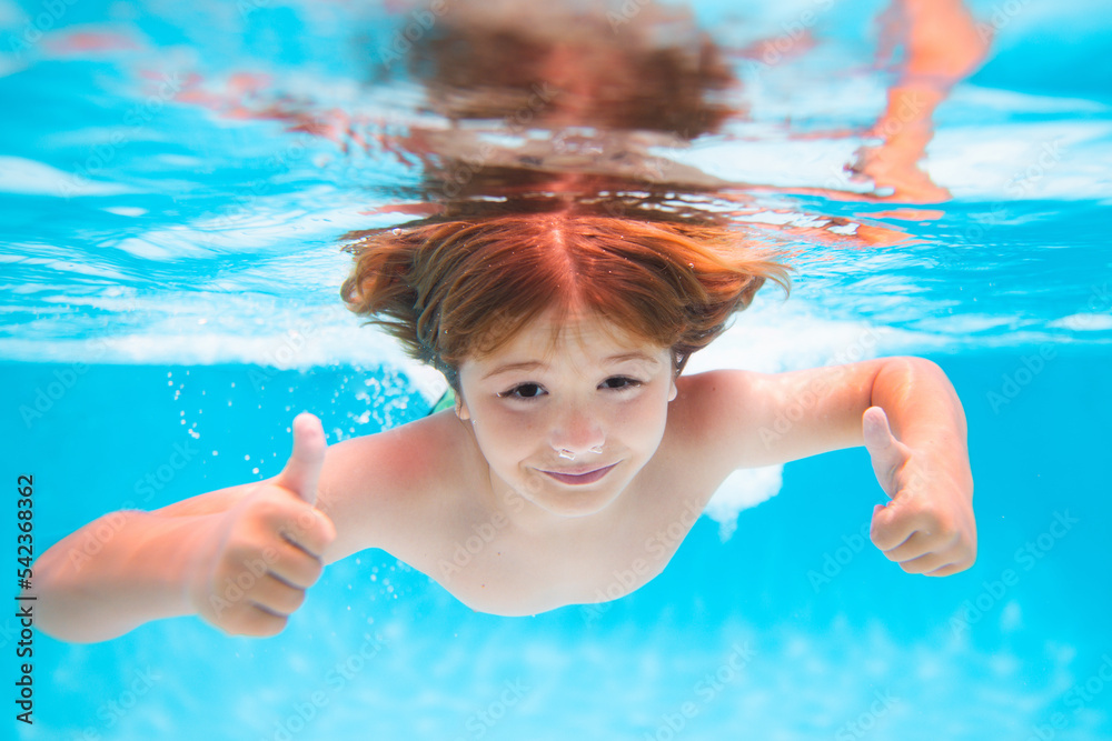 Child splashing in swimming pool. Kid swimming in pool underwater ...
