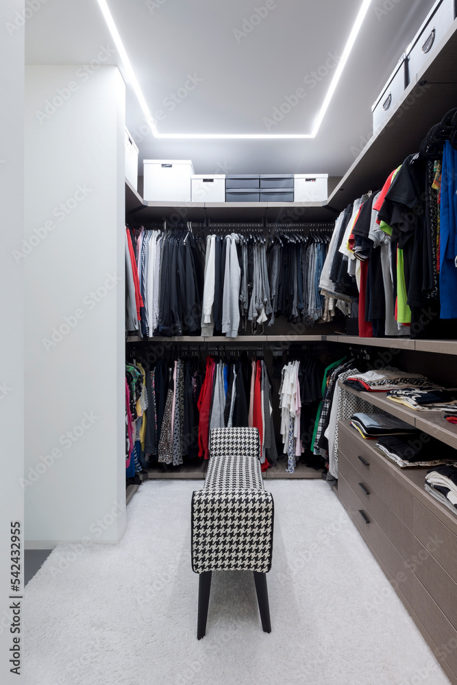 Front view walk-in closet full of clothes and in the center is a ...