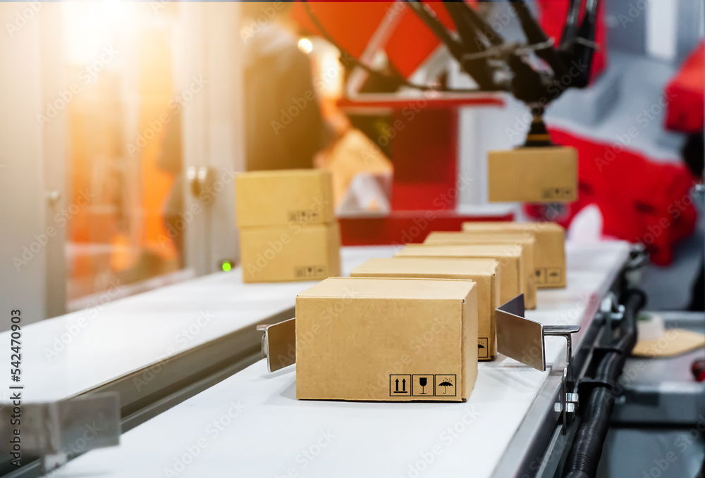 Cardboard boxes on conveyor, robotic arm picked up the blurry box ...