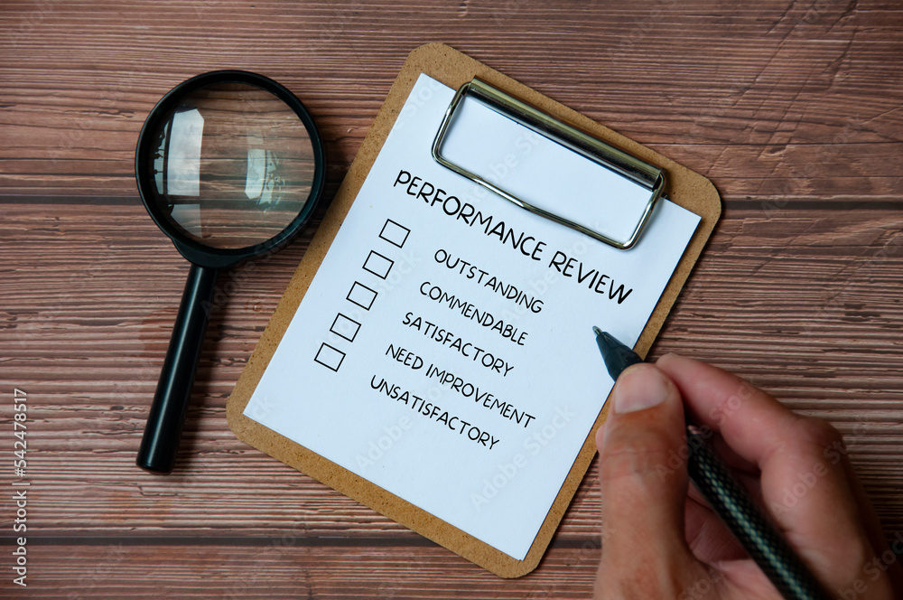 Top view of performance review checklist on clip board with hand ...