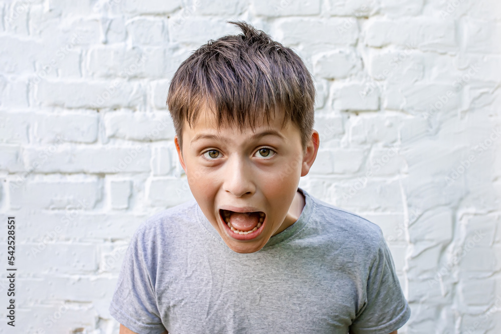 The funny boy yells with his mouth wide open and his eyes bulging. An ...