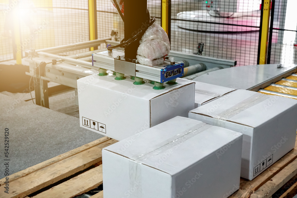 Industrial robot arm loading carton on the parade in manufacturing ...