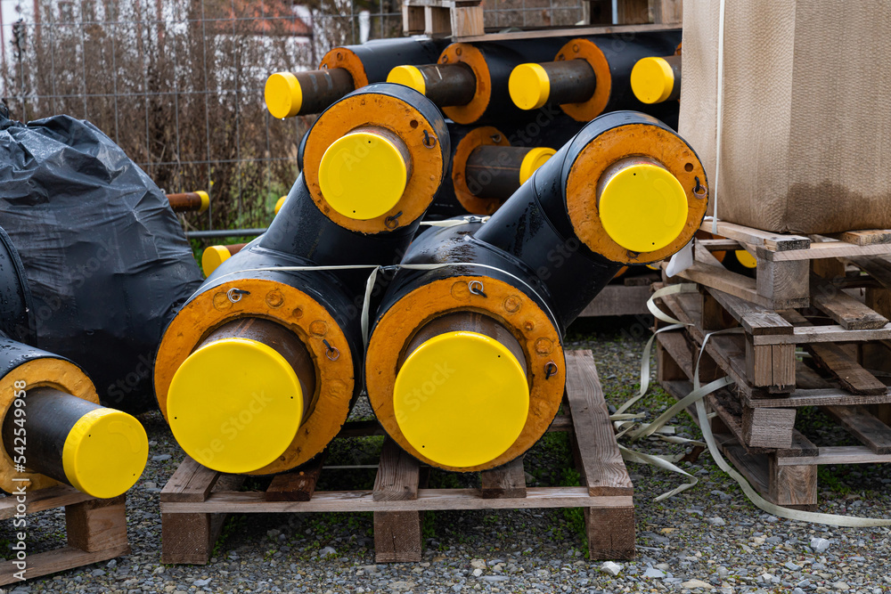 Black pipe splitters lying on pallets at a construction site. Yellow ...