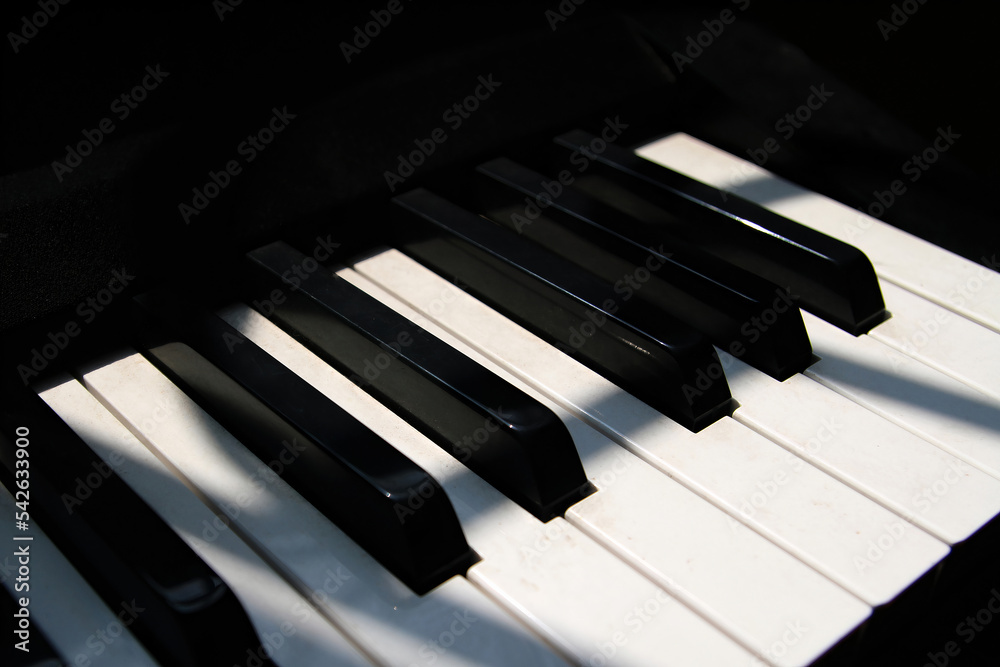 Close up view of piano keyboard near window with shadow overlay effect ...