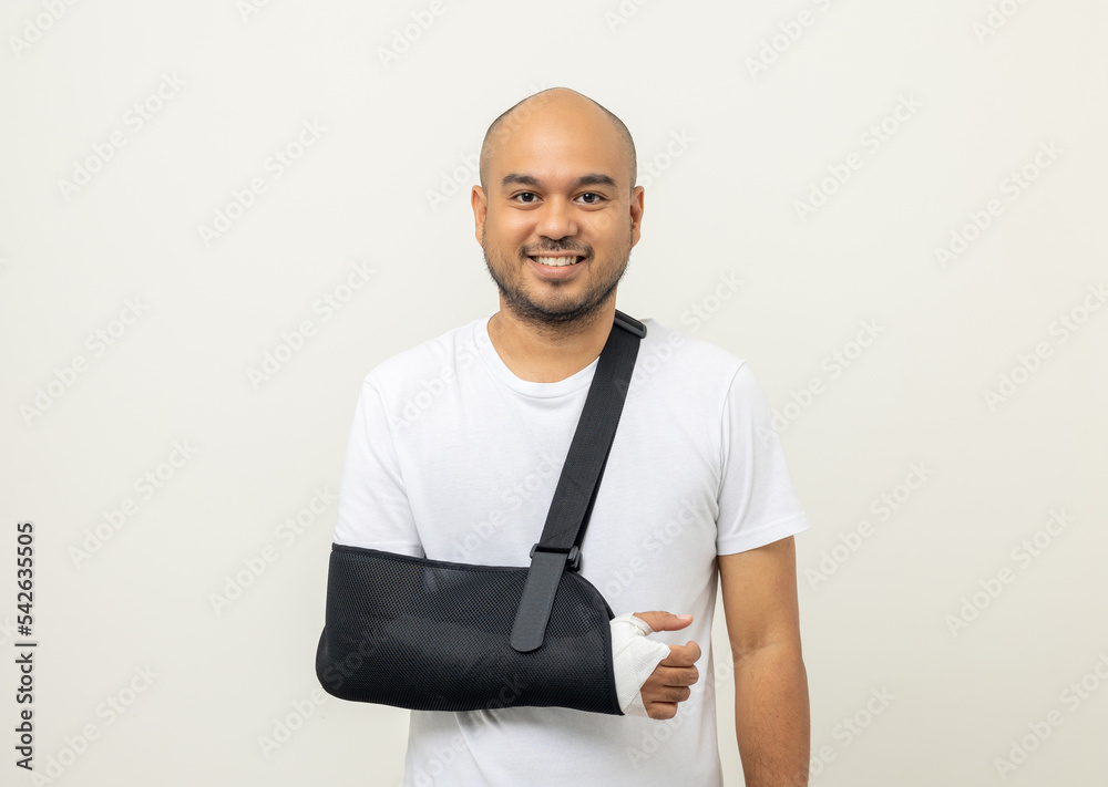 Happy young asian man broken arm on isolated background. Asian man put ...