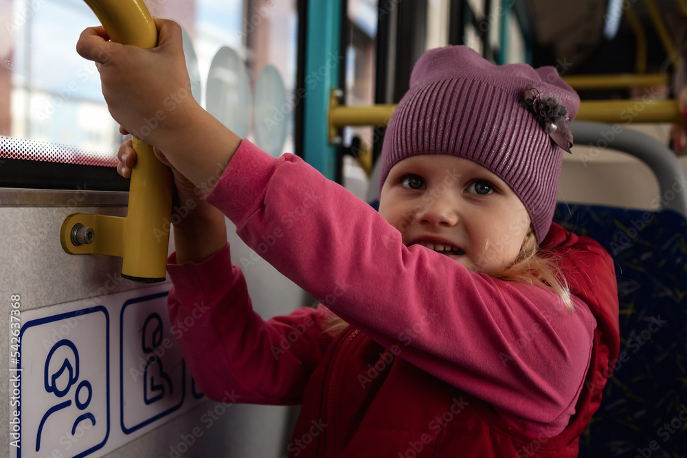 Child rides bus of public modern transport looks out window. Little ...