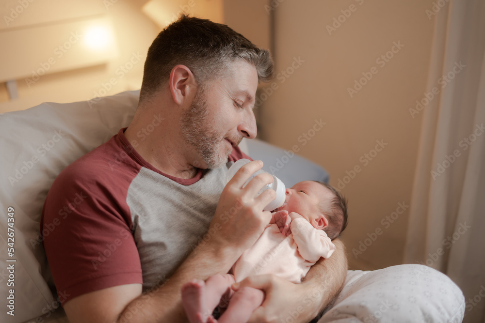 lifestyle portrait of proud happy man holding tenderly bottle feeding ...