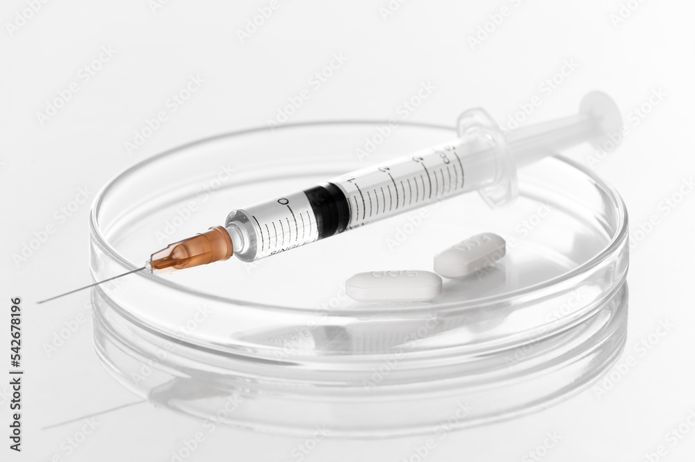 Syringe with liquid transparent vaccine for injection and white pills ...