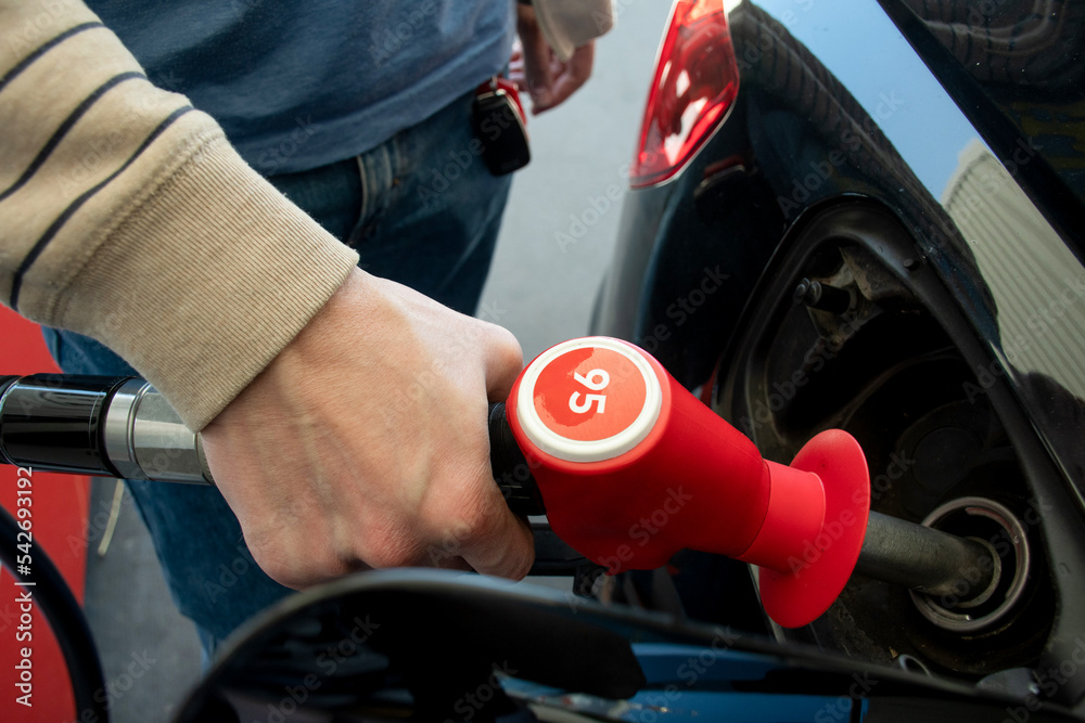 A man hand holding pump filling gasoline. Pumping 95 petrol into the ...