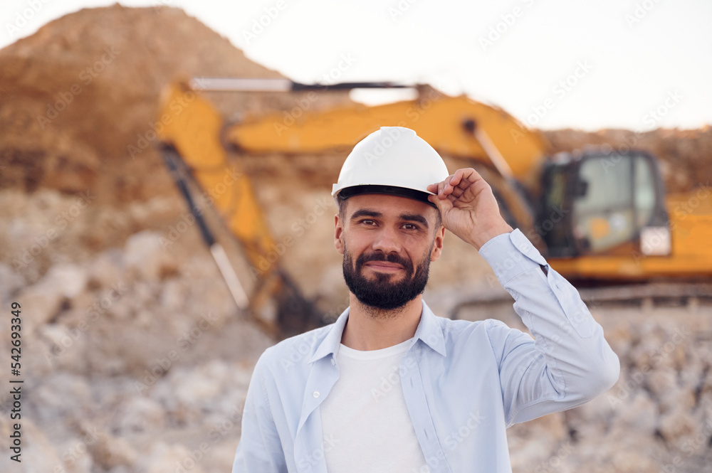 Standing against excavator. Man in uniform is working in the quarry at ...