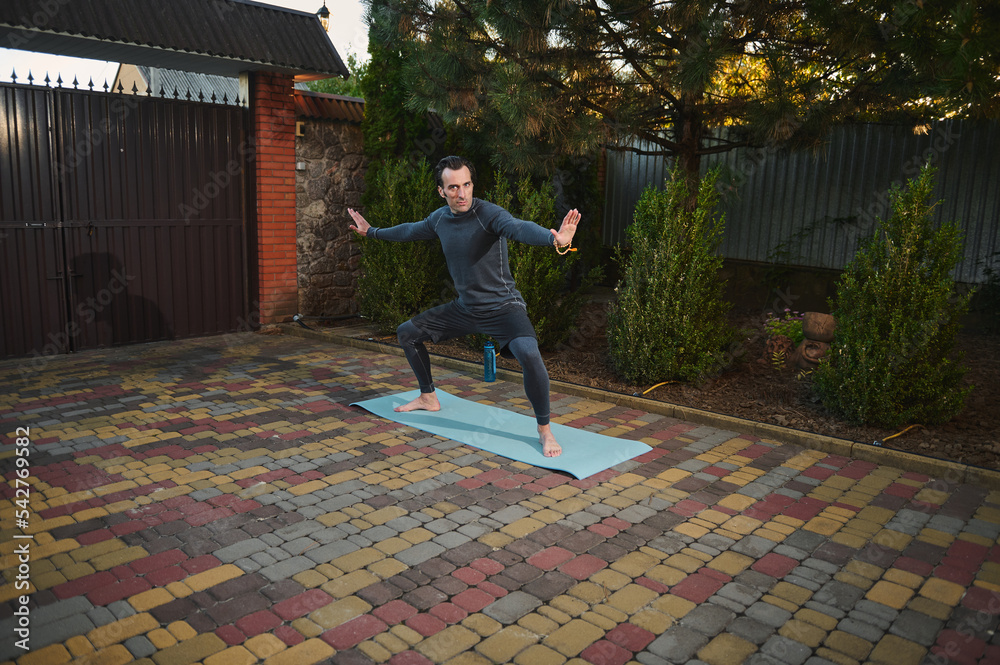 Full length man doing balancing stick pose, warrior three pose outdoors ...
