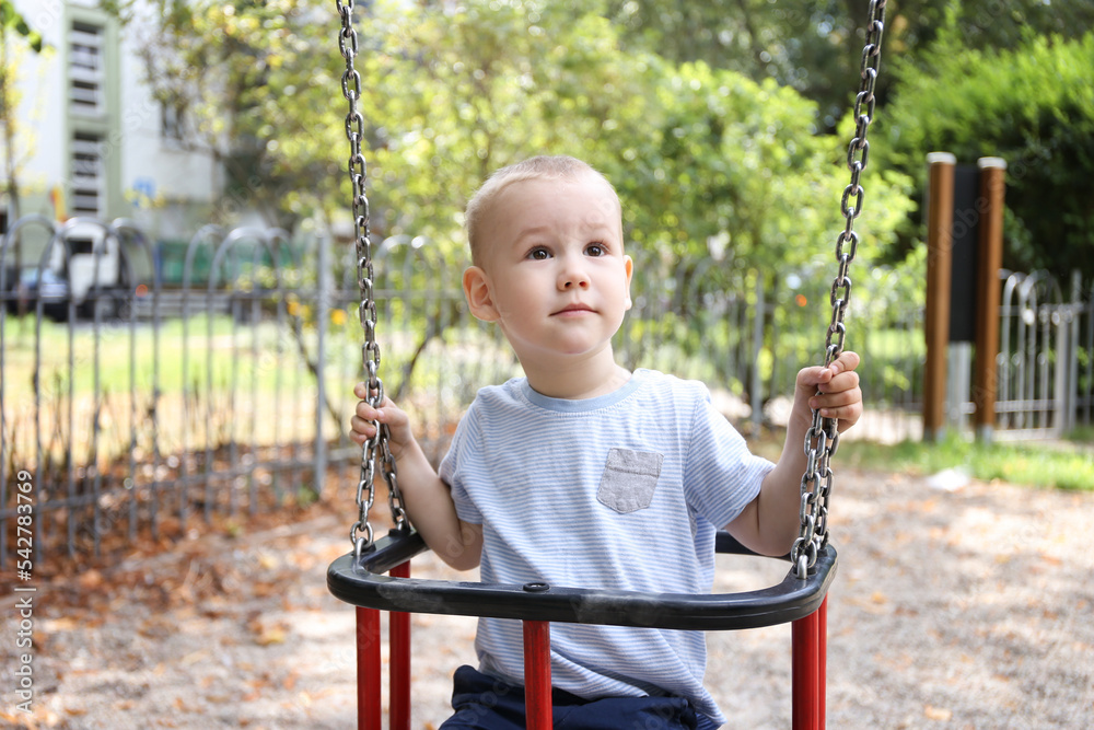 2 year old child playing in the playground in summer, happy child ride ...
