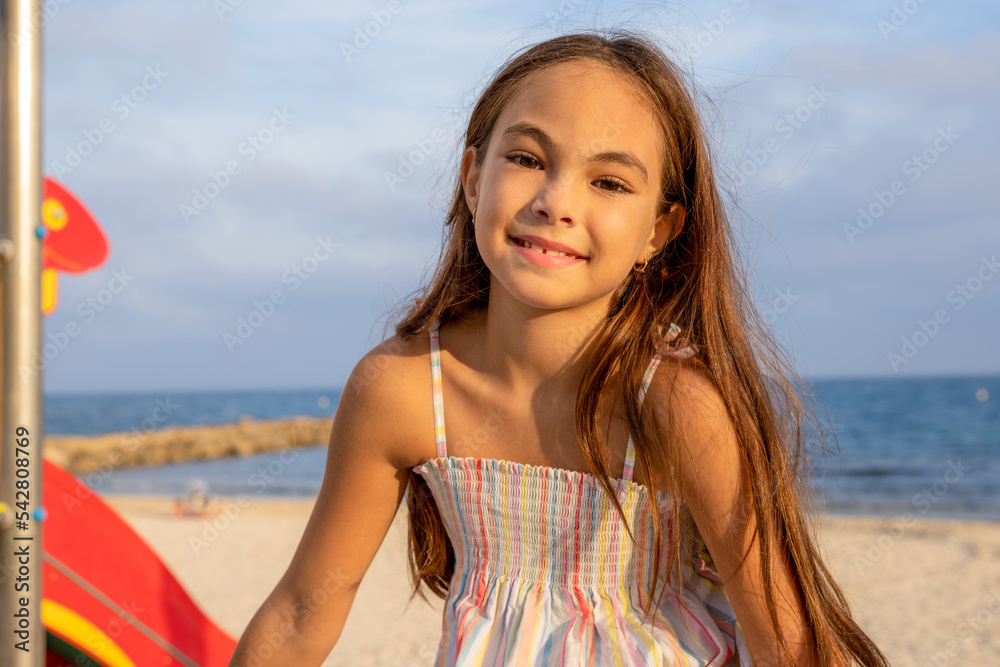 Little cute child girl in playground on the beach with smile on summer ...