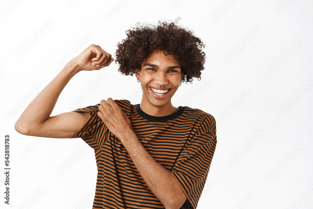 Handsome young slim boy, laughing and showing biceps, flexing muscles ...