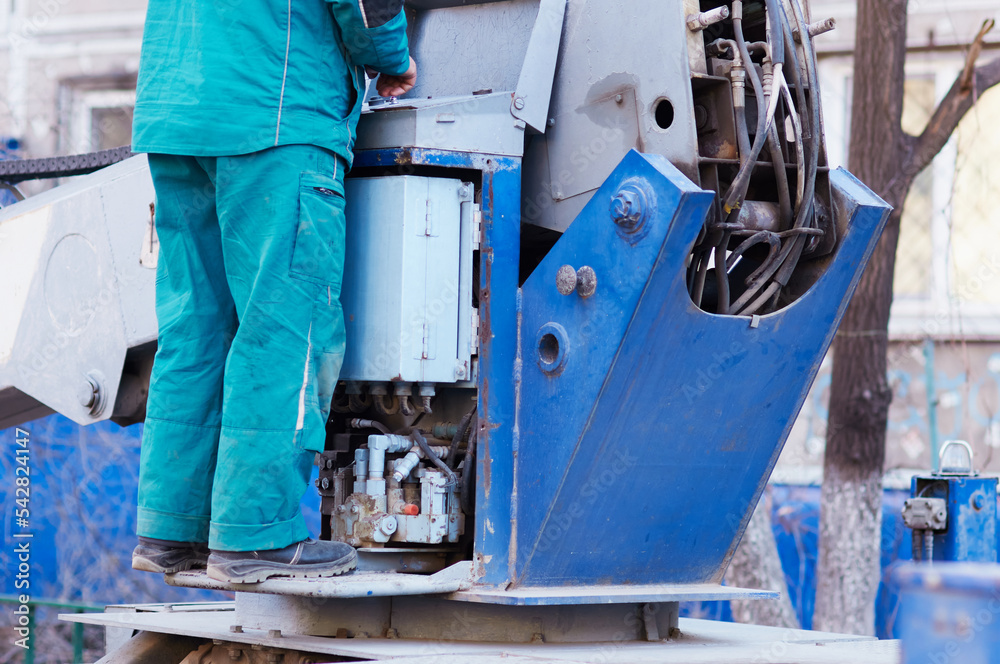 An operator in a blue working uniform operates an aerial platform ...